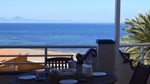 Uma varanda com uma mesa posta para dois, com vista para a praia e o mar.