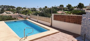 Piscina com escada de metal, rodeada por um muro baixo com painéis de treliça decorativa.