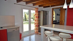Cozinha equipada com lava-louças, frigorífico e área de refeições com banquetas.