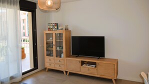 Sala de estar com um armário de madeira, uma televisão de tela plana e uma luminária pendente trançada.