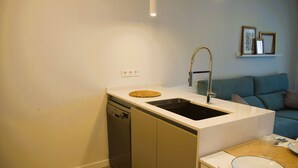 Uma cozinha compacta com máquina de lavar louça, pia e pequena área de refeições com mesa posta para dois.