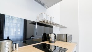 Uma cozinha moderna com fogão por indução preto, eletrodomésticos de aço inoxidável e uma máquina de café em uma prateleira.