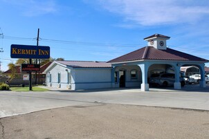 Kermit Inn com fachada azul, uma torre do relógio e área de estacionamento coberta.