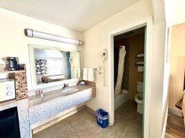 Casa de banho com lavatório, espelho, secador de cabelo e chuveiro.