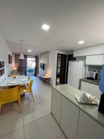 Cozinha moderna com área de jantar, armários brancos e um grande dispensador de água.