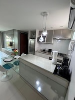 Cozinha moderna com ilha central, eletrodomésticos de aço inoxidável e mesa de jantar de vidro.