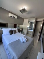 Quarto de hotel com uma cama grande, televisão de tela plana, espelho e ar condicionado.