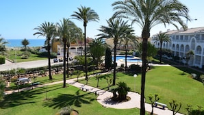 Um resort com piscina, palmeiras e vista para o mar.