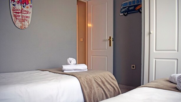 Quarto de hotel com duas camas, uma porta e um enfeite na parede.