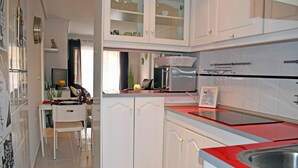 Uma cozinha moderna com armários brancos, bancada vermelha e pia de aço inoxidável.