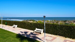 Um calçadão à beira-mar com bancos e um poste de luz, com vista para o oceano.