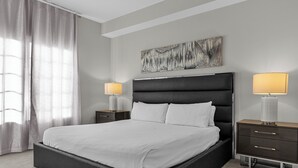Quarto moderno com cama grande, duas mesas de cabeceira e cabeceira.