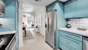 Uma cozinha moderna com armários verde-água, eletrodomésticos de aço inoxidável e um design limpo e iluminado.