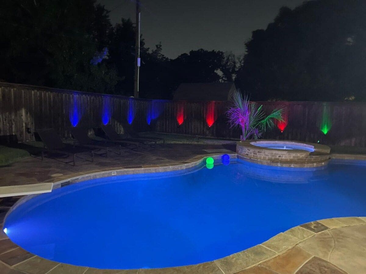 Piscina com hidromassagem, rodeada por um deck de madeira e uma cerca.
