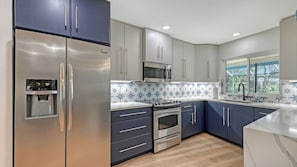 Uma cozinha moderna com eletrodomésticos de aço inoxidável, um bebedouro e um micro-ondas.
