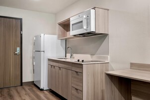 Uma cozinha compacta com geladeira, micro-ondas, pia e armários de madeira.