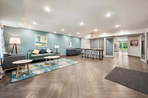 Uma sala de estar moderna com um sofá, duas mesinhas, uma mesa de centro e um espaço de jantar com cadeiras.