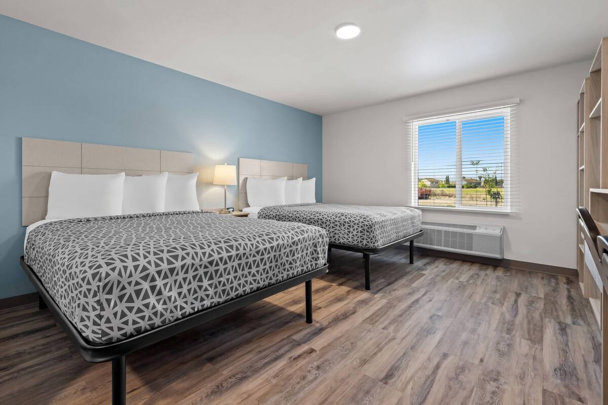 Quarto com duas camas, janela com persianas, radiador e vista para o exterior.