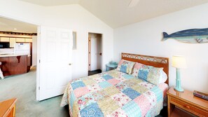 Quarto com cama, mesa de cabeceira, abajur e um objeto decorativo na parede.