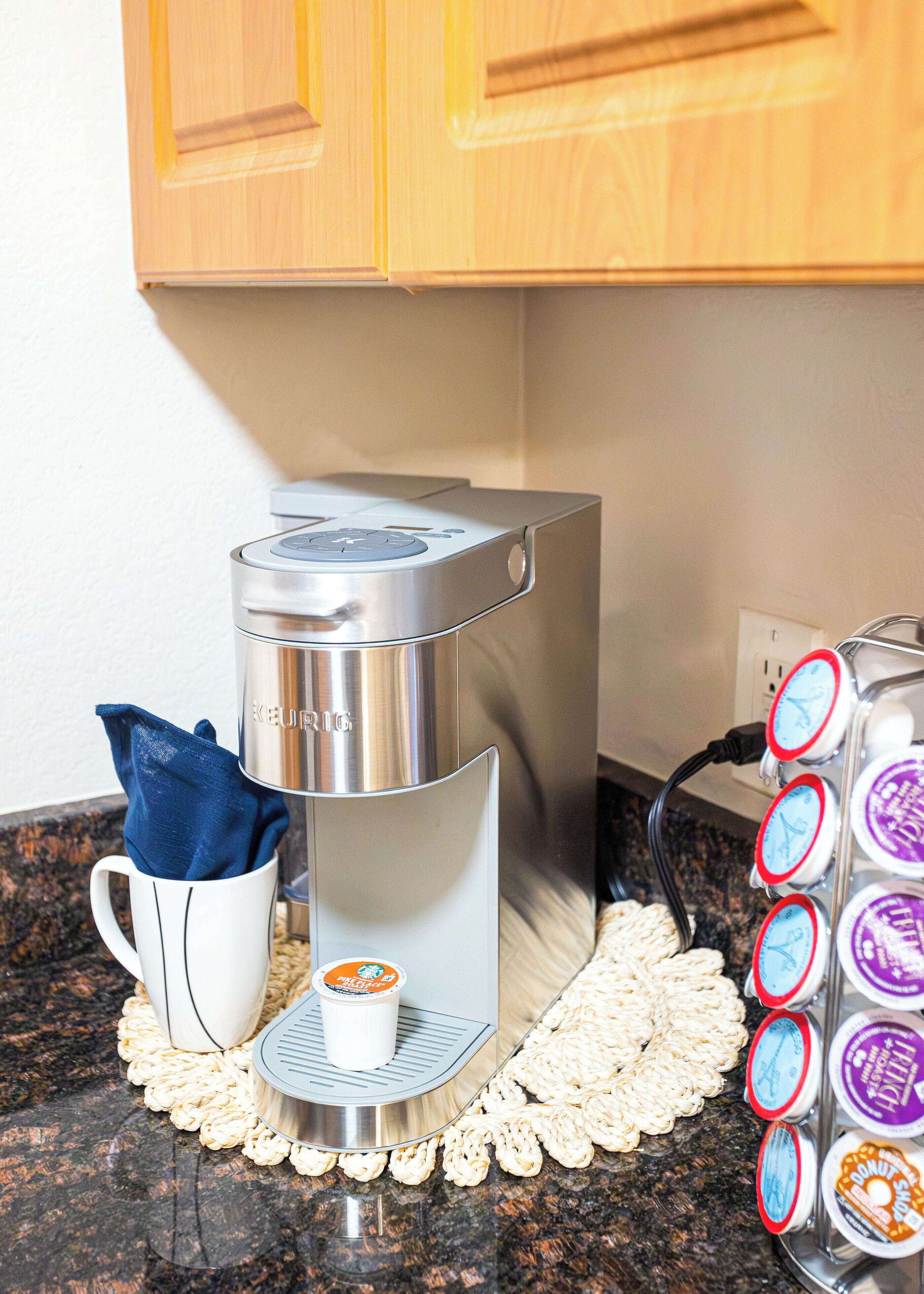 Máquina de café com uma chávena e um prato de pastelaria numa bancada de cozinha.