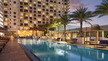 Um hotel com piscina, espreguiçadeiras e palmeiras.