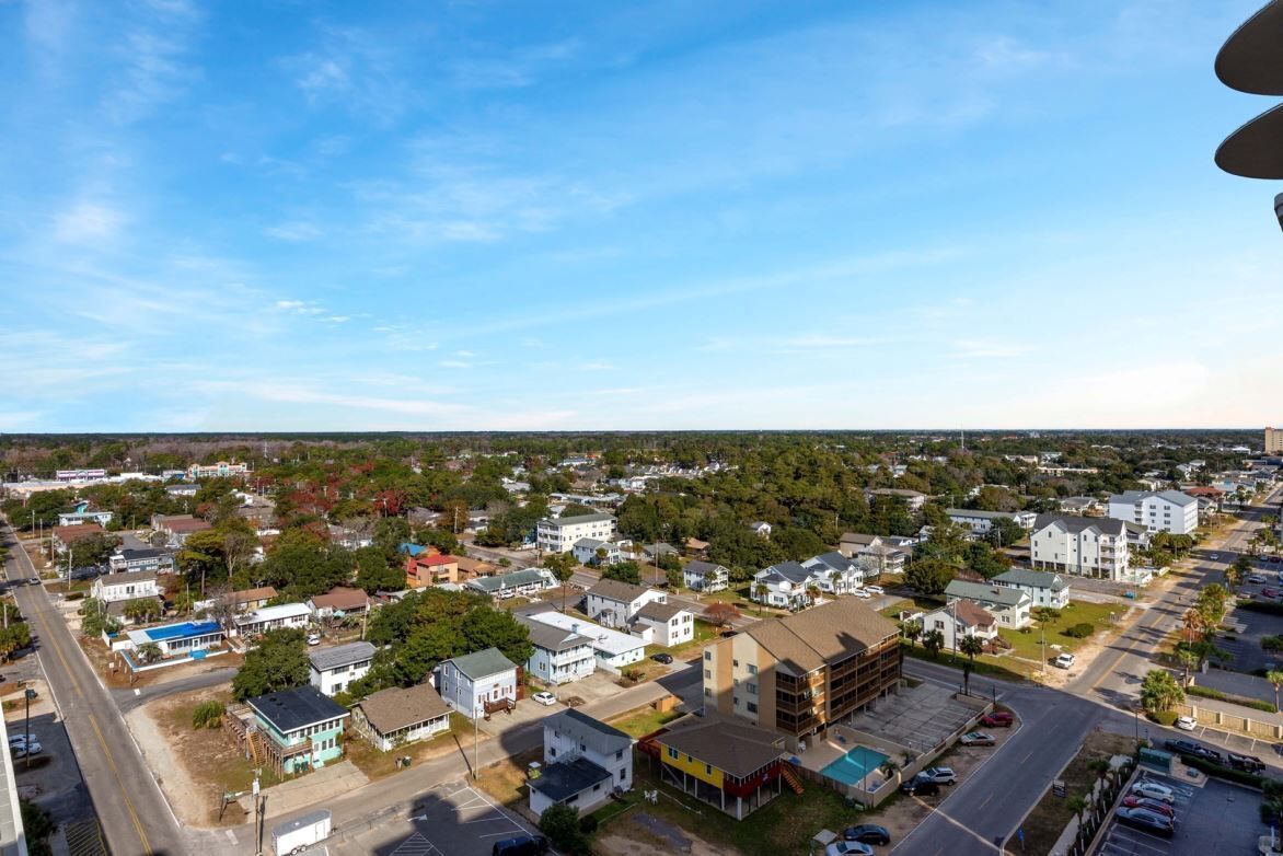 Vista aérea de uma área residencial com casas, ruas e céu claro.