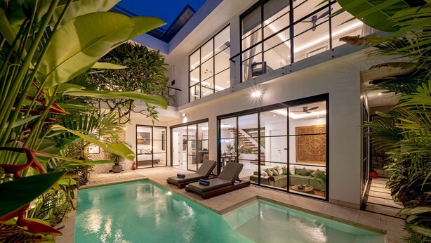 Uma casa moderna com piscina, janelas amplas e área de estar externa.