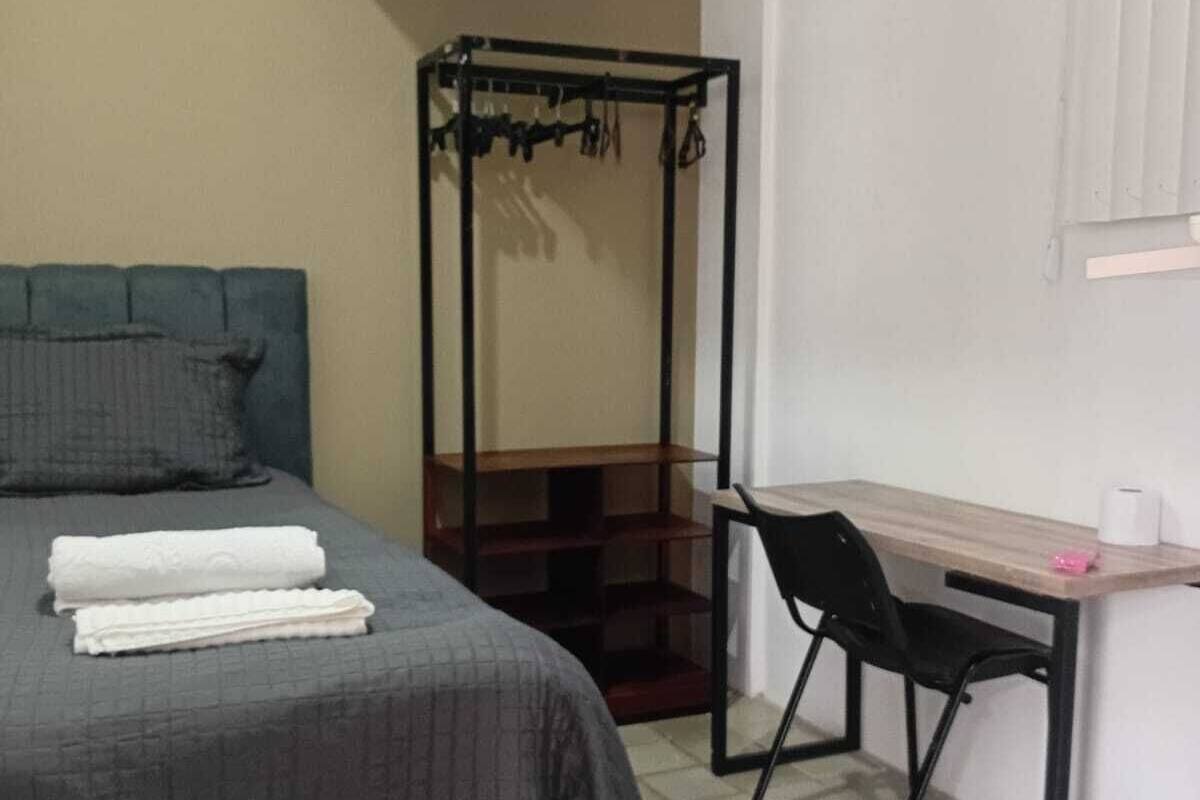 Um quarto com uma cama, uma escrivaninha e uma cadeira.