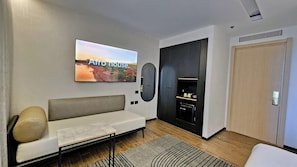 Uma sala de estar moderna com sofá, televisão de tela plana, lareira e uma porta.