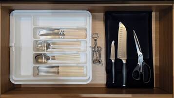 Uma gaveta com um conjunto de facas, abridor de garrafa e diversos utensílios.