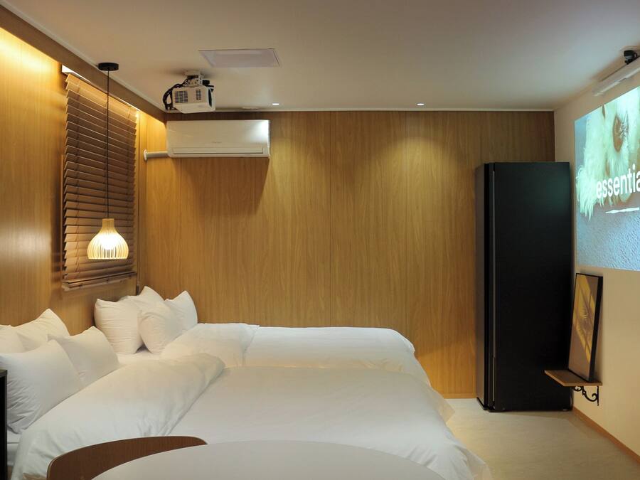 Quarto de hotel com cama, televisão de tela plana, projetor e geladeira.