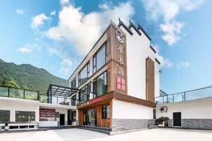 Um hotel moderno com estrutura em dois andares, grandes janelas e uma varanda.