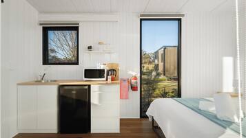Quarto compacto com cama e vista para o exterior.