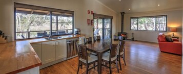 Cozinha espaçosa com mesa de jantar, cadeiras e uma grande janela com vista para um deck.
