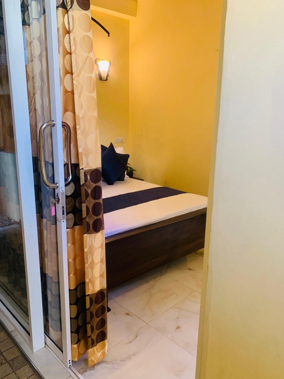 Quarto com cama, área de chuveiro e luminária fixada na parede.