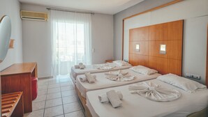 Quarto de hotel com duas camas, cabeceira de madeira, escrivaninha, espelho e janela com cortinas.