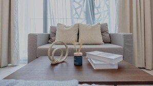 Sala de estar com sofá, almofadas, mesa de centro, um adorno circular, castiçal e livros.