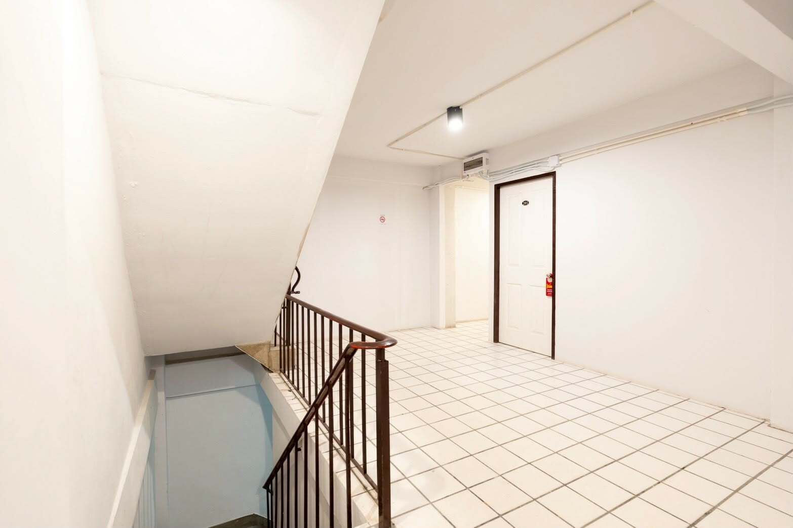 Um corredor limpo e revestido com azulejos, com uma escadaria que dá para um patamar.