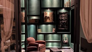 Quarto com sofá de couro, uma mesinha e uma parede decorativa com estantes.