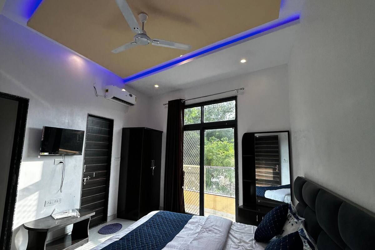 Quarto moderno com cama, ventilador de teto e vista para o verde lá fora.