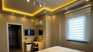 Quarto moderno com cama, escrivaninha e cadeira, aparelho de ar condicionado e janela com persianas.