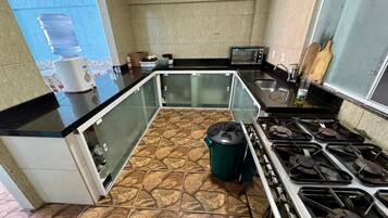 Cozinha com fogão a gás, bebedouro e lixeira.