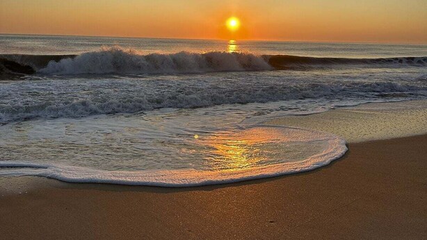Uma praia com ondas ao pôr do sol.