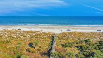 Uma estrada costeira que leva a uma praia, com vista clara para o oceano.