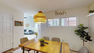 Uma área de refeições com uma mesa de madeira, cadeiras, um lustre e uma placa na parede que diz "Beach".