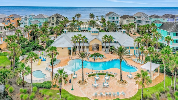 Um resort com uma piscina grande, palmeiras e vista para o oceano.