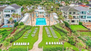Um resort com piscina central, vários quartos de hóspedes e um gramado bem cuidado com espreguiçadeiras.