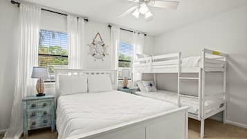 Quarto com uma cama de solteiro, uma cama beliche, um ventilador de teto e uma janela com cortinas.