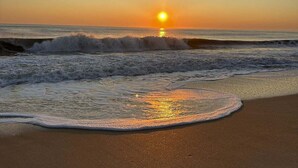Uma praia com ondas ao pôr do sol.