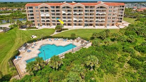 Um hotel com vários andares, piscina, rodeado por vegetação e vista para a paisagem.